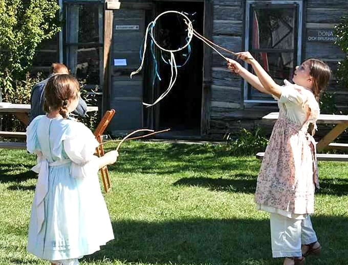 Children try their hand at "graces," a popular 19th-century game requiring coordination and skill rather than batteries or Wi-Fi.