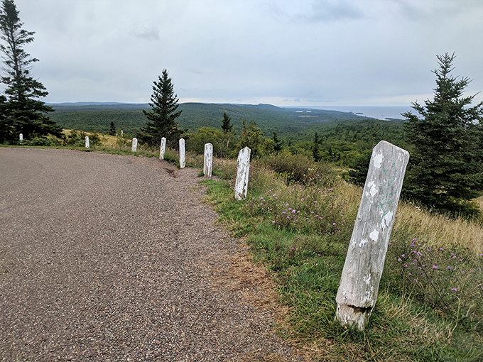 White markers stand sentinel along the mountain's edge, guiding adventurers safely while framing the breathtaking panorama beyond.