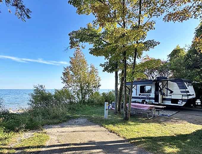 A travel trailer enjoys prime lakefront real estate, proving you don't need a passport for postcard-worthy camping views.