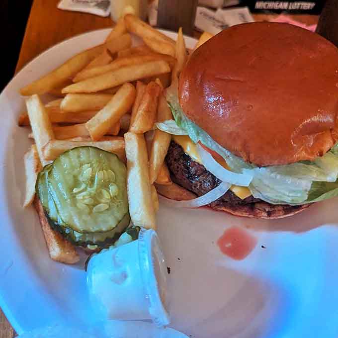 A perfectly assembled burger alongside golden onion rings, the kind of simple pleasure that makes you wonder why anyone bothers with fancy food.