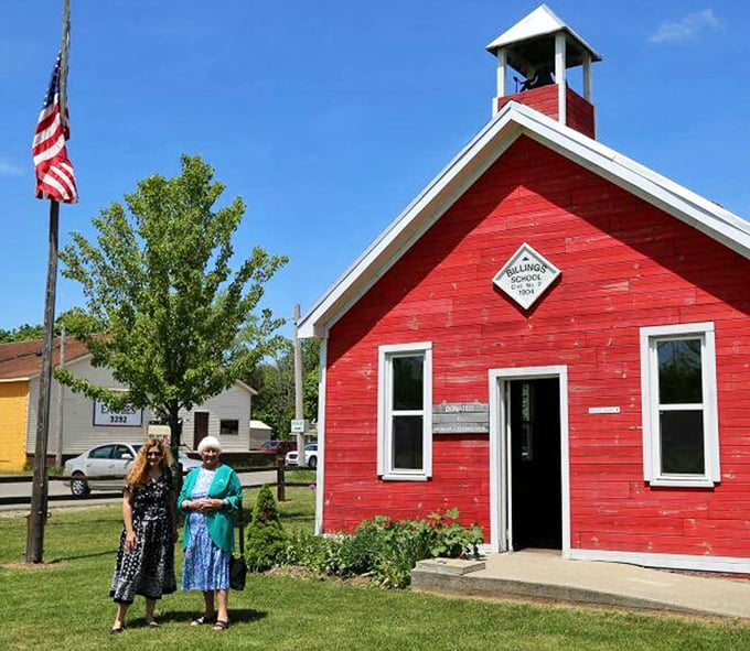 Visitors pose proudly beside the schoolhouse, perhaps contemplating how different their own educational experiences were from frontier learning.