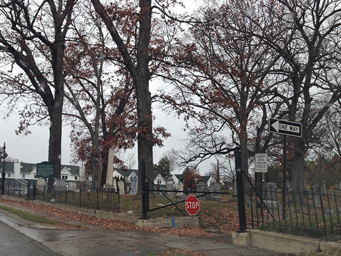 The cemetery's ornate iron gate stands sentinel, separating the world of the living from this peaceful garden of remembrance.