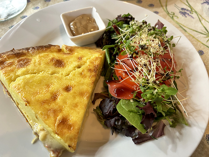 The quintessential quiche arrives with a perfectly crisp crust, silky interior, and fresh side salad &ndash; French simplicity at its finest.