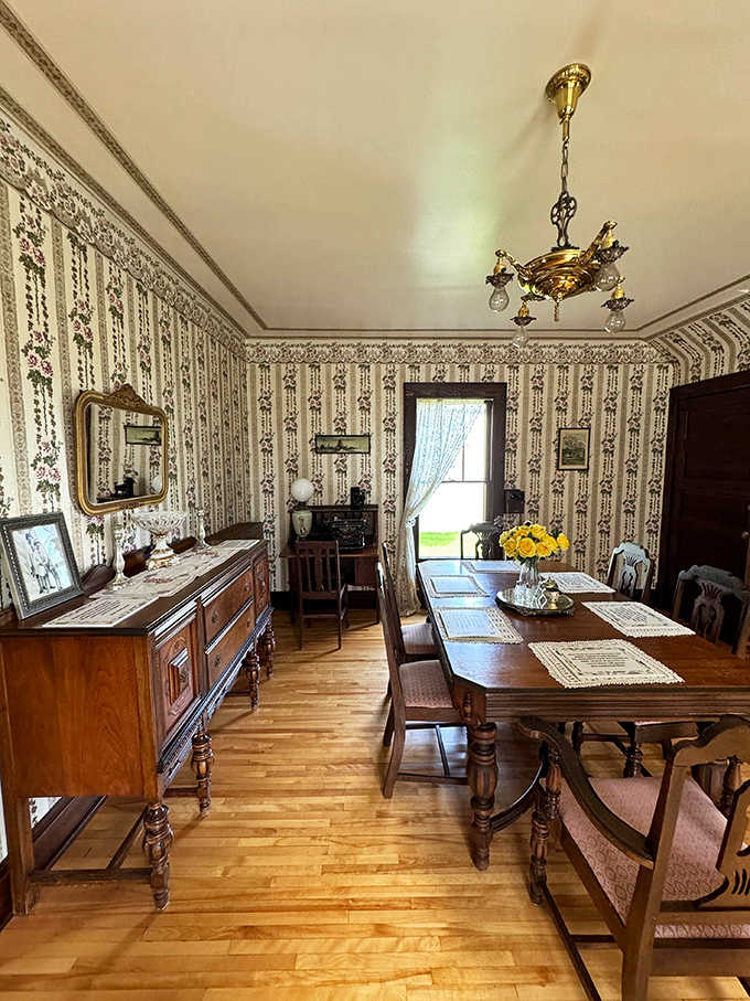 The formal dining room showcases period-appropriate decor with floral wallpaper and polished wood furniture that the Gumm family might have gathered around.