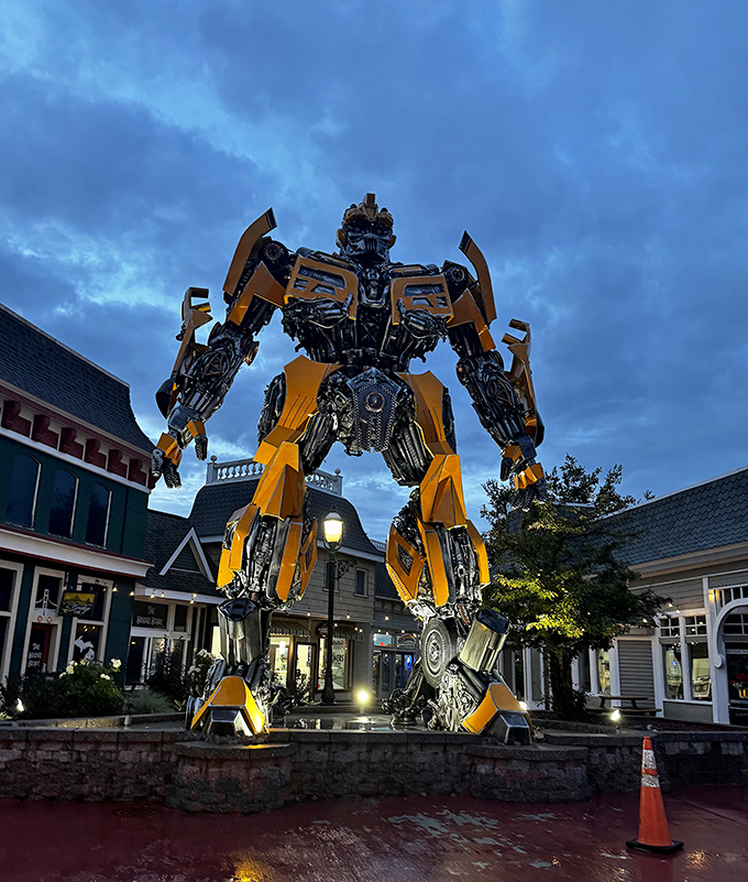 As dusk falls, strategic lighting transforms Mack-A-Tron into an even more dramatic presence, standing watch over the shopping district like a mechanical night guardian.