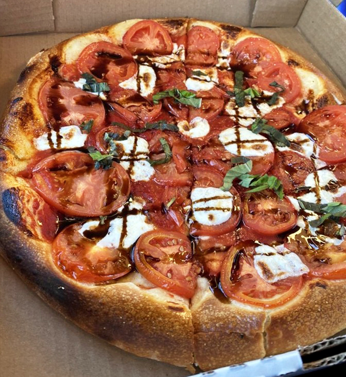 Fresh tomatoes, basil, and what appears to be a balsamic drizzle create a pizza that's as visually stunning as it is delicious.
