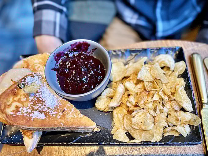 The Monte Cristo reimagined: powdered sugar dusts a golden-fried exterior while house-made jam awaits alongside crispy potato chips.