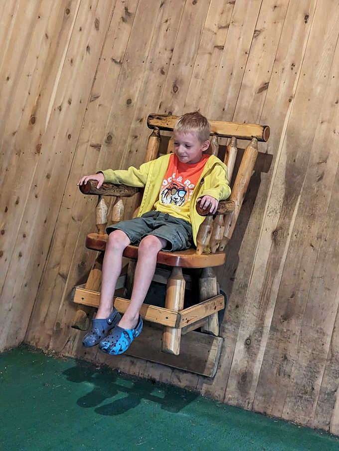 A young visitor experiences the famous floating chair illusion, his expression worth a thousand scientific explanations about forced perspective.