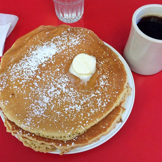 Pancakes so fluffy they practically float off the plate, dusted with powdered sugar and topped with a melting pat of butter.