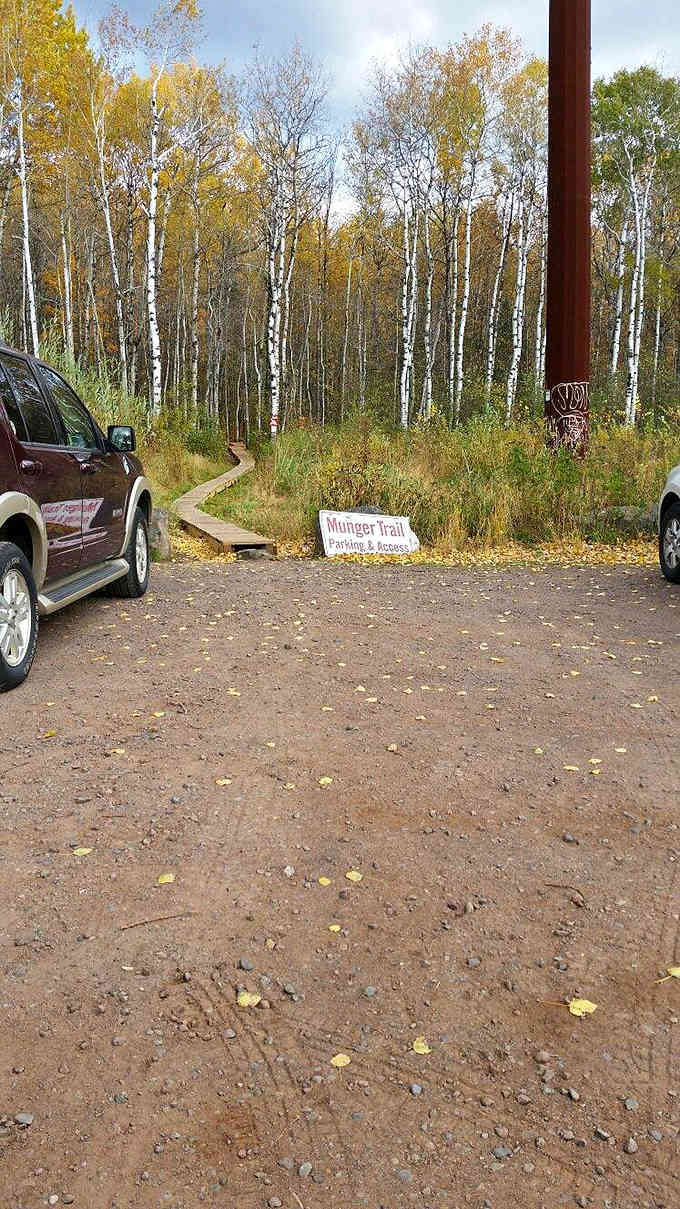 The Munger Trail parking area welcomes adventurers with a wooden sign and birch trees standing at attention like nature's honor guard.