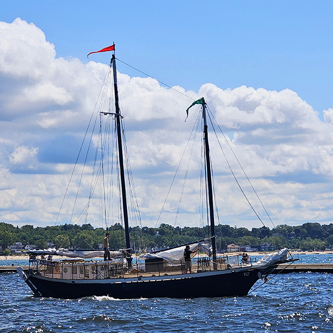 This magnificent sailing vessel glides past the lighthouse, creating a timeless scene that connects modern visitors to Michigan's rich maritime heritage.
