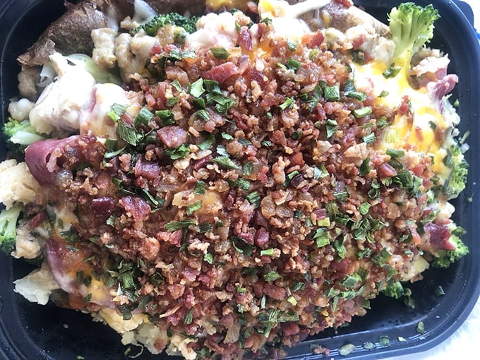 The Jefferson Potato arrives like royalty, crowned with a generous sprinkle of bacon bits and fresh herbs that elevate it beyond mere comfort food.