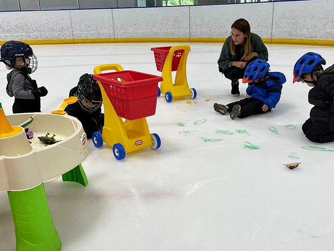 Young skaters navigate the ice with determination, some using training aids that add splashes of color to their learning journey.
