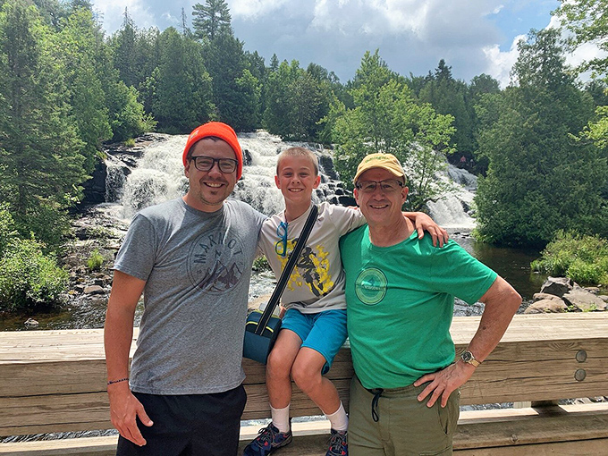 Happy hikers celebrating nature's majesty at Bond Falls, where the water doesn't just fall – it performs an elaborate dance down the rocks.