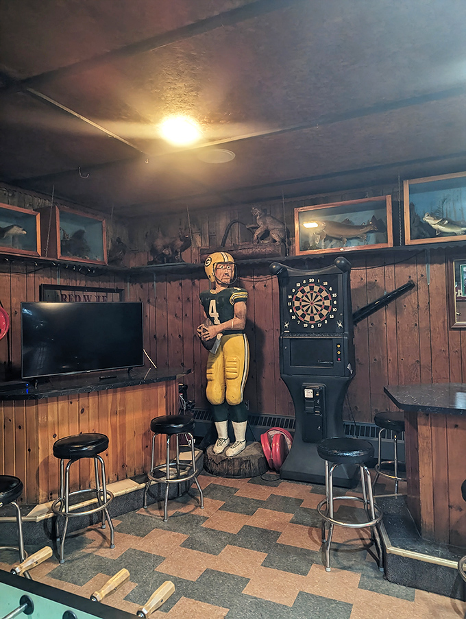 Sports fans find their happy place in this corner featuring a life-sized Packers player statue, mounted game trophies, and a dartboard for friendly competition.