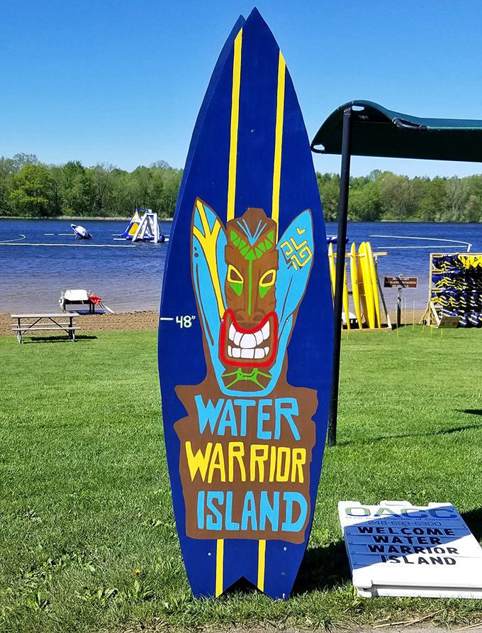 The iconic Water Warrior Island surfboard welcomes visitors with its tiki-inspired grin, promising adventures beyond the shore.