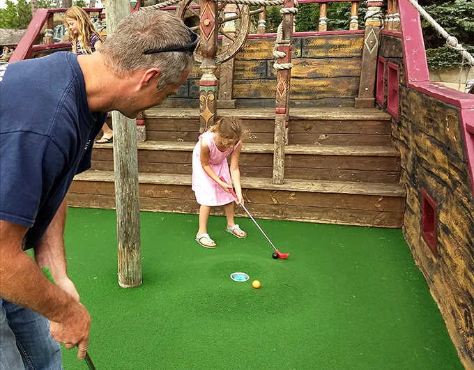 Generations connect over the universal language of mini-golf, where parental guidance meets childhood determination on the greens.