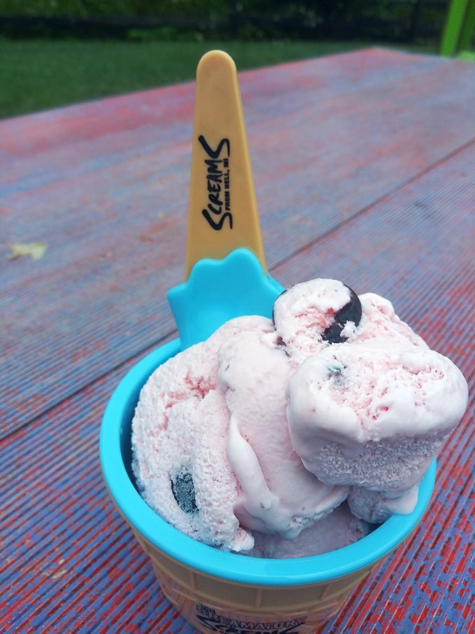 A scoop of creamy delight awaits in a bright blue cup, proving that even in Hell, Michigan, there are sweet rewards for the brave.