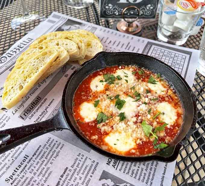 Bubbling shakshuka arrives in its own cast iron skillet, the eggs perfectly poached in spiced tomato sauce, begging for that crusty bread to dive in.