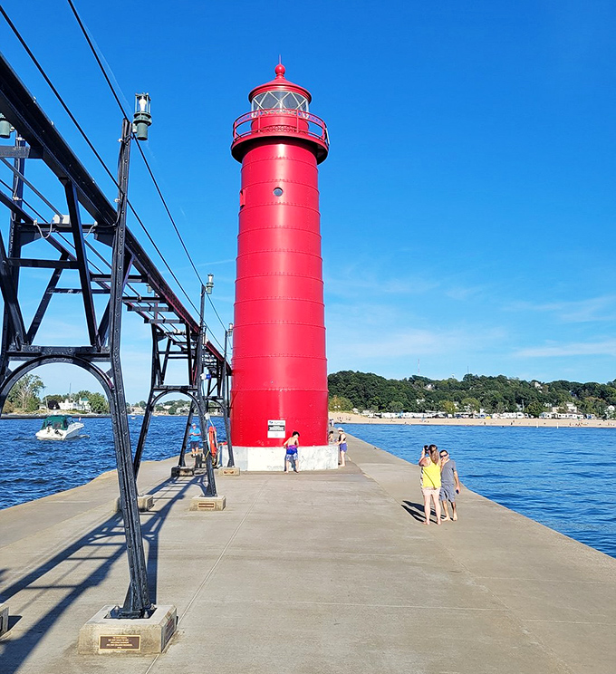 The lighthouse tower stands tall against blue skies, its vibrant red paint job making it impossible to miss from any angle.