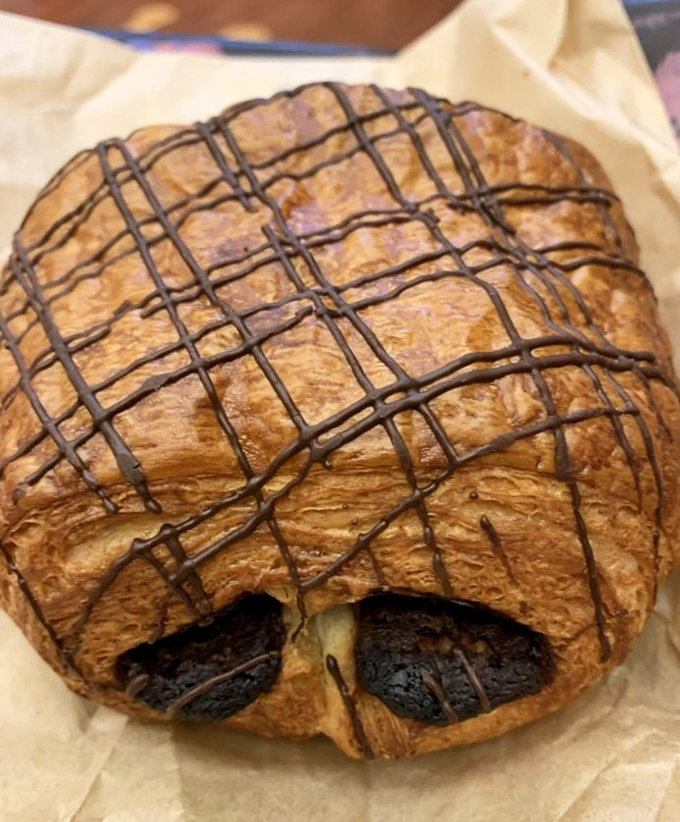 Chocolate croissants with layers so buttery and flaky they shatter on contact, revealing pockets of dark chocolate that melt into the warm, honeycomb interior.