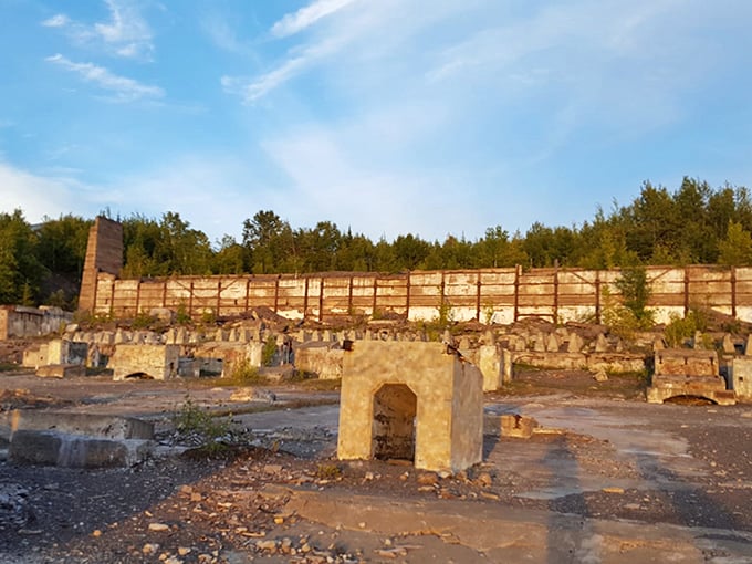 The concrete retaining wall stands like a forgotten theater backdrop, still waiting for industrial actors who exited the stage decades ago.