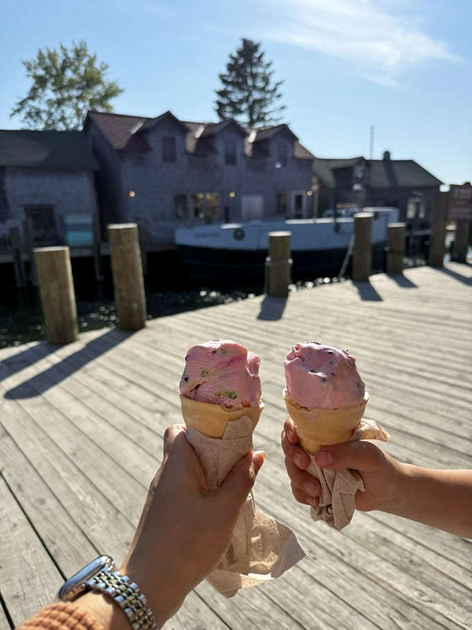 Two ice cream cones raised in a sweet toast against the backdrop of Leland's waterfront &ndash; summer in Michigan doesn't get better than this.