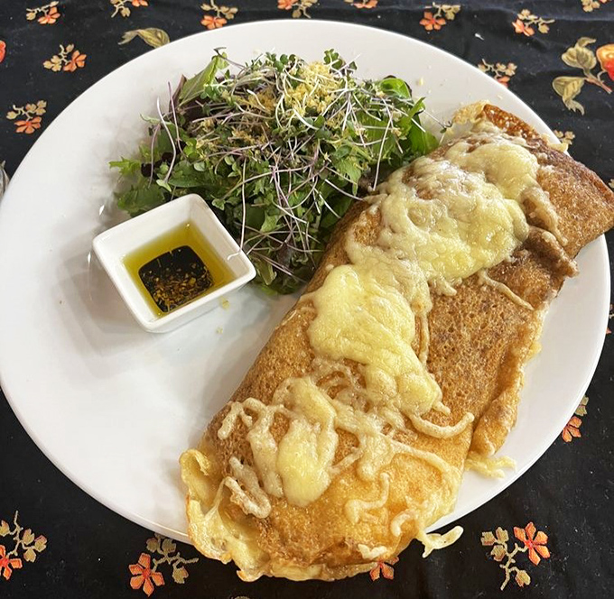 A delicate crepe cradles melted cheese and mushrooms, topped with fresh microgreens &ndash; proof that French cuisine elevates even the simplest ingredients.