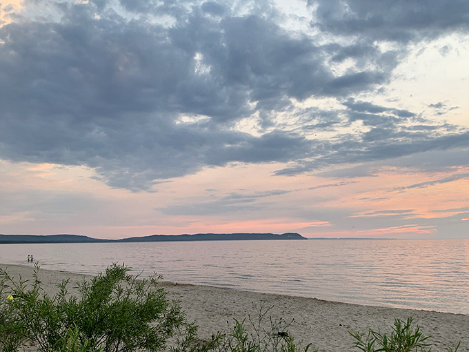 Twilight transforms Good Harbor Bay into a watercolor painting, where pink-tinged clouds meet the gentle rhythm of evening waves.