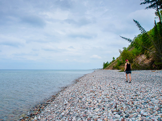 Pebbled shores meet endless horizon as a solitary explorer contemplates the vastness of this Great Lakes treasure.