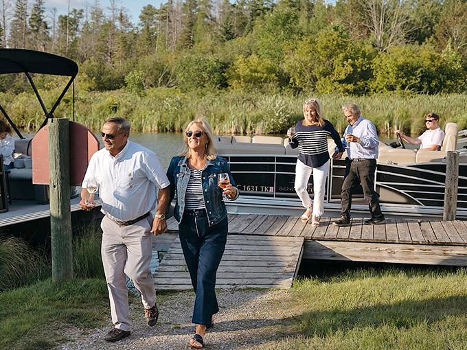 The ultimate Michigan wine country arrival &ndash; guests toast with glasses in hand as their pontoon docks at the vineyard's waterfront entrance.