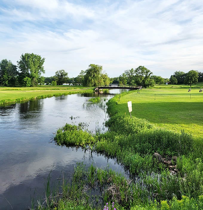 A serene water feature cuts through lush fairways, creating both a picturesque scene and a challenging obstacle for golfers.