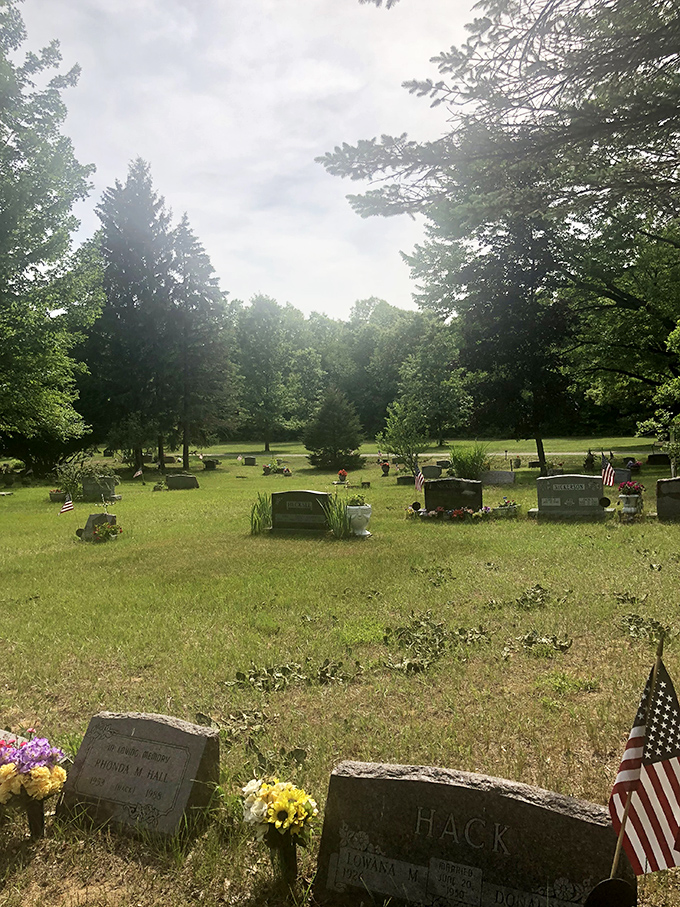 American flags flutter among the headstones in this sunlit section, where generations of families have created a peaceful community of remembrance.