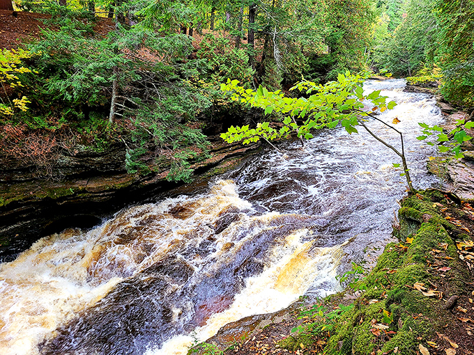 The Presque Isle River carves its ancient path through stone, a liquid highway that's been flowing since before maps existed.