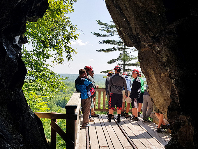 The payoff view: adventurers gather on a wooden platform overlooking Michigan's verdant landscape, a welcome sight after hours underground.