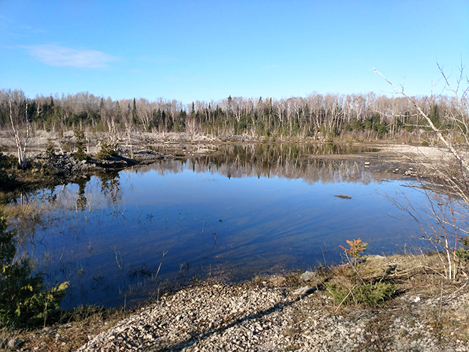 Mirror-like waters reflect the sky where limestone dust once filled the air, creating a tranquil oasis in this industrial time capsule.