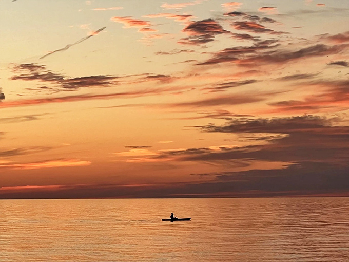 Solitude on the water: A lone paddler drifts across the golden canvas of sunset, finding that perfect moment of peace.