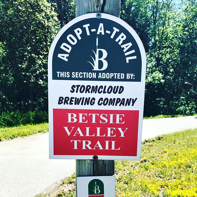 Trail signage reveals local businesses care enough to adopt sections, proving even breweries understand the importance of a good path.