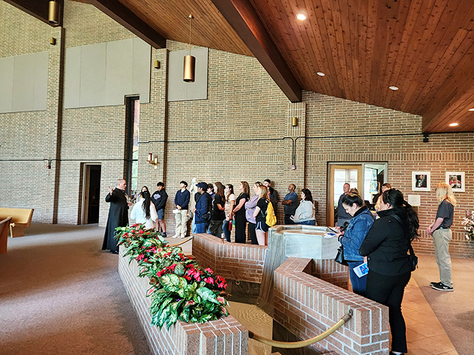 Visitors gather around the baptismal font, listening intently as the spiritual significance of this sacred space is explained.