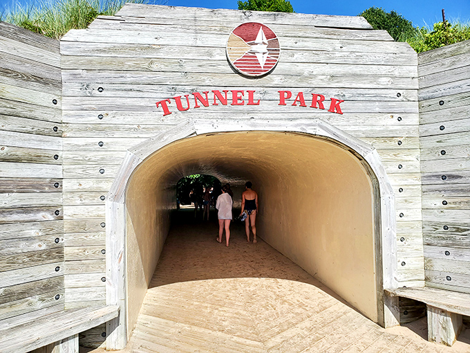 Beachgoers emerge from the tunnel's cool shade into brilliant sunshine, like actors stepping onto nature's grandest stage.