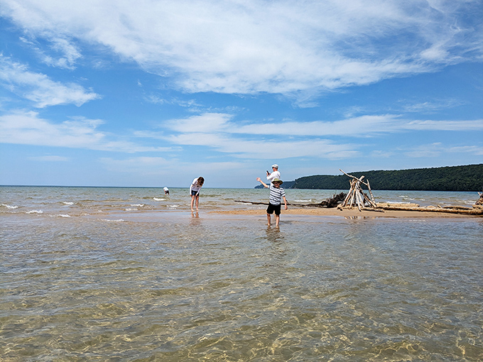 Kids building sandcastles with Grand Island in the background is basically the Upper Peninsula version of a perfect childhood memory being made in real-time.