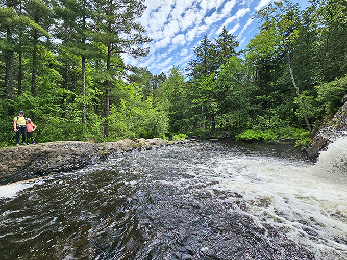 Visitors explore the waterfall's edge, drawn to the mesmerizing power of water doing what it's done for millennia.