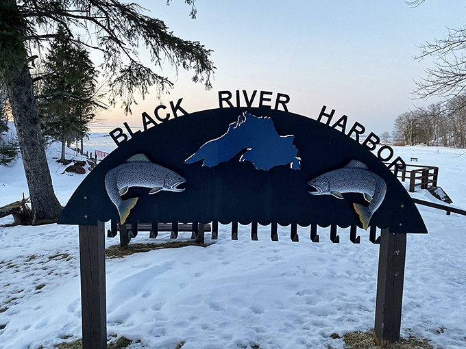 The Black River Harbor sign frames Lake Superior's vastness beyond, marking the gateway to some of Michigan's most pristine shoreline.