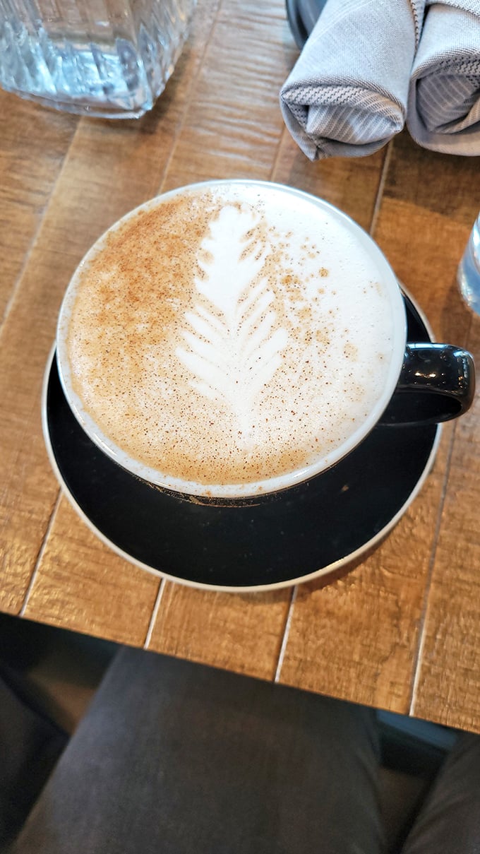 Artful foam crowns this cappuccino, the barista's careful hand creating a moment of beauty before the first delicious sip.