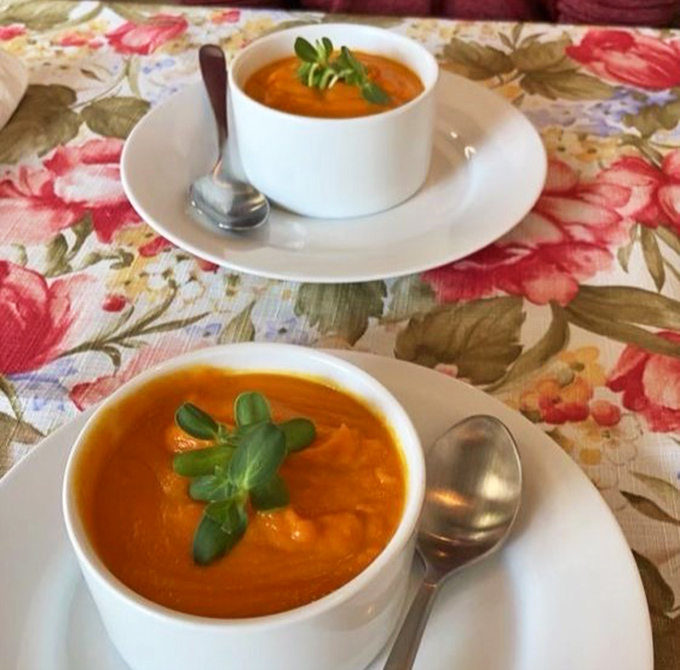 Velvety carrot bisque, garnished with fresh herbs, offers a warm embrace in a bowl &ndash; the kind of soup that makes you close your eyes in appreciation.