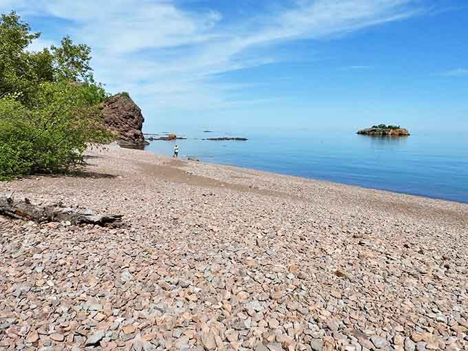 Multicolored stones peek through clear waters along the shore, creating an ever-changing natural art installation.