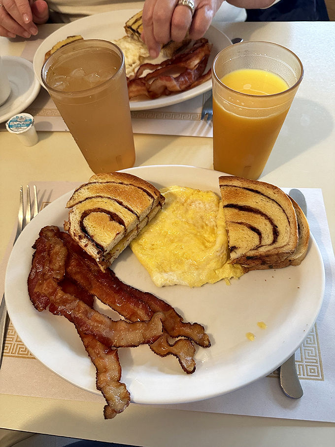 Breakfast plates arrive loaded with fluffy eggs, crispy bacon, and that gorgeous cinnamon swirl bread that makes regular toast weep with inadequacy.