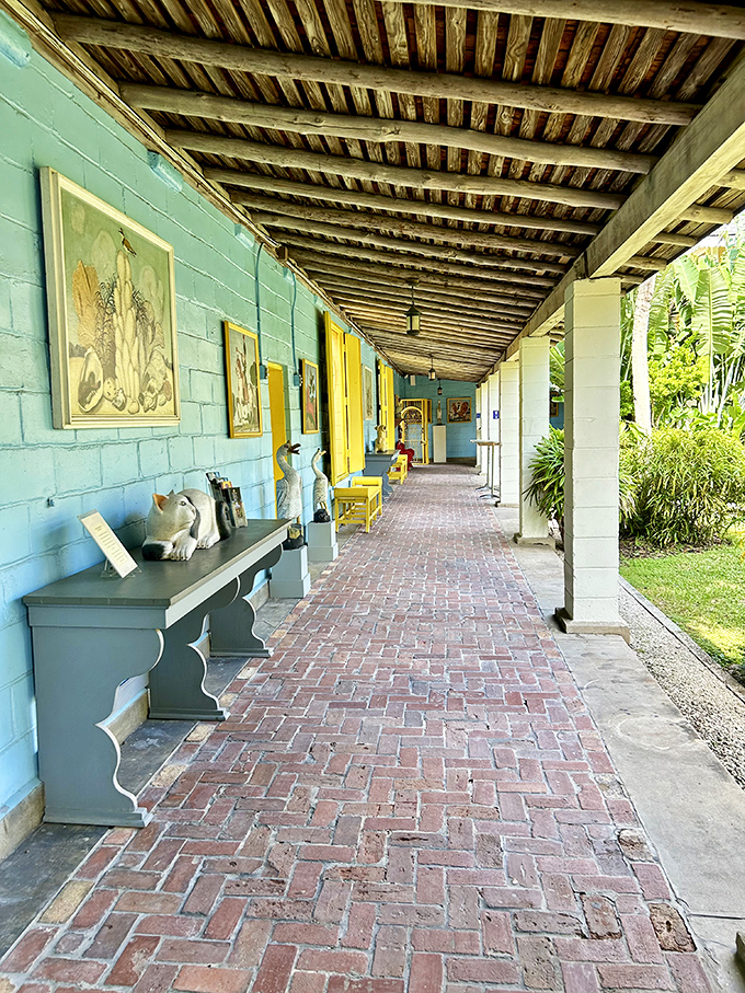 The covered walkway invites wandering, its turquoise walls and brick floor creating a cool passage between tropical worlds.