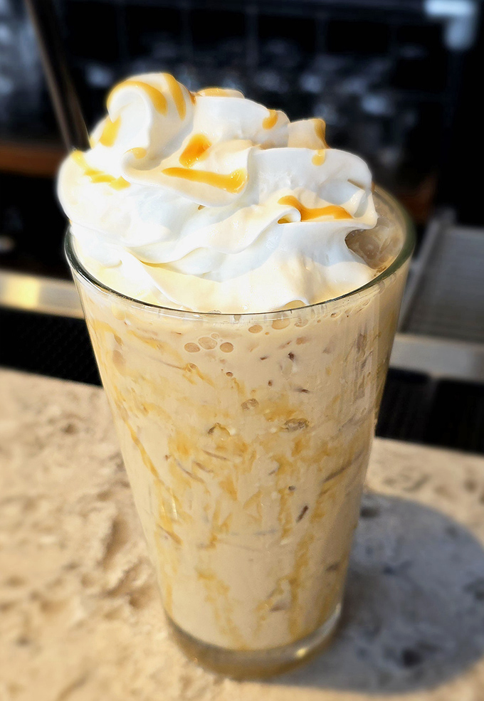 Whipped cream mountains and caramel rivers top this iced coffee creation – dessert and caffeine joining forces in one glorious glass.