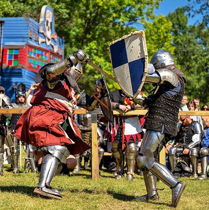 Armored combatants clash shields and swords in choreographed battle, their authentic gear weighing upwards of 60 pounds in the Michigan heat.